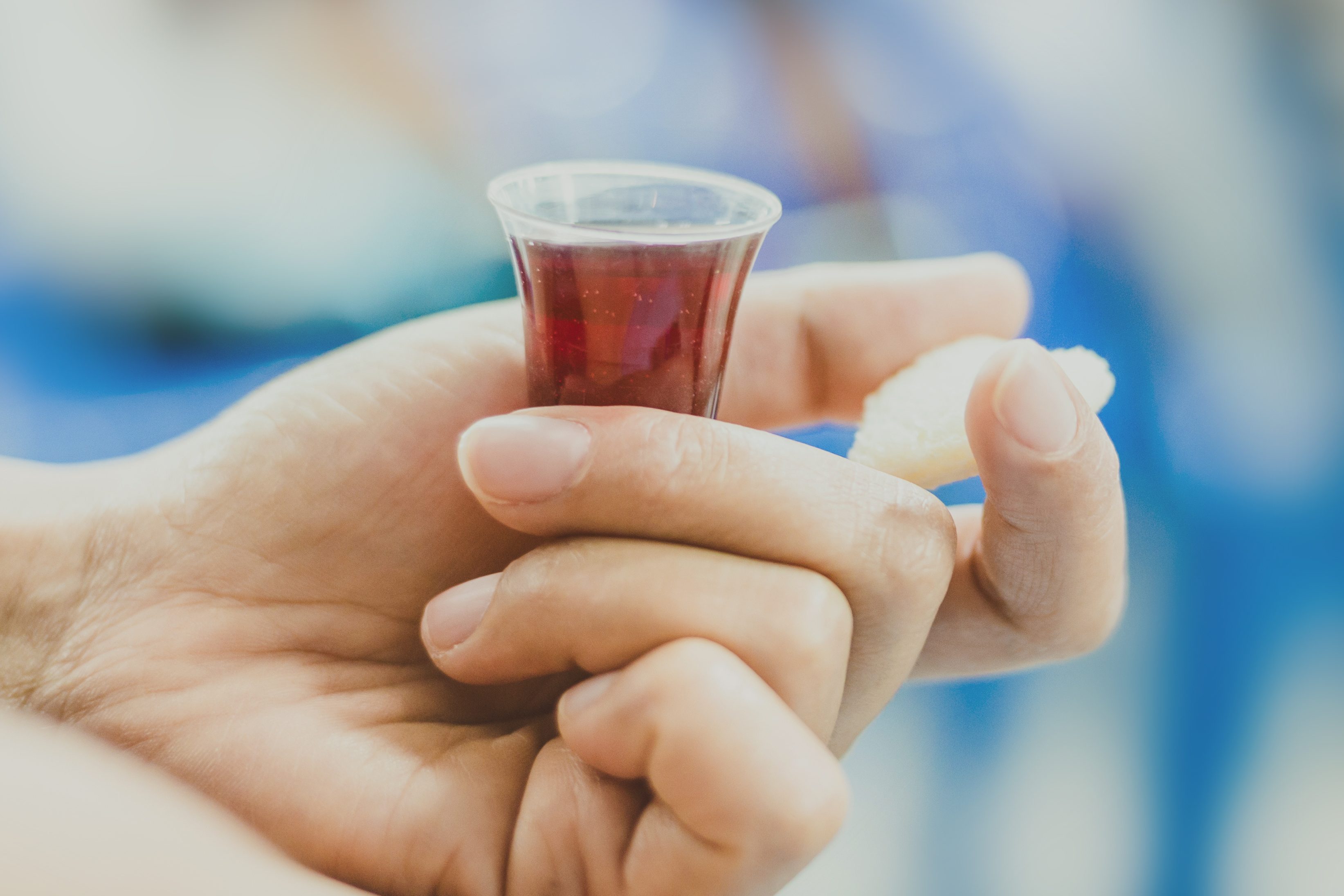 Hands hold a red wine cup in Holy communion – Beyond the Dalet